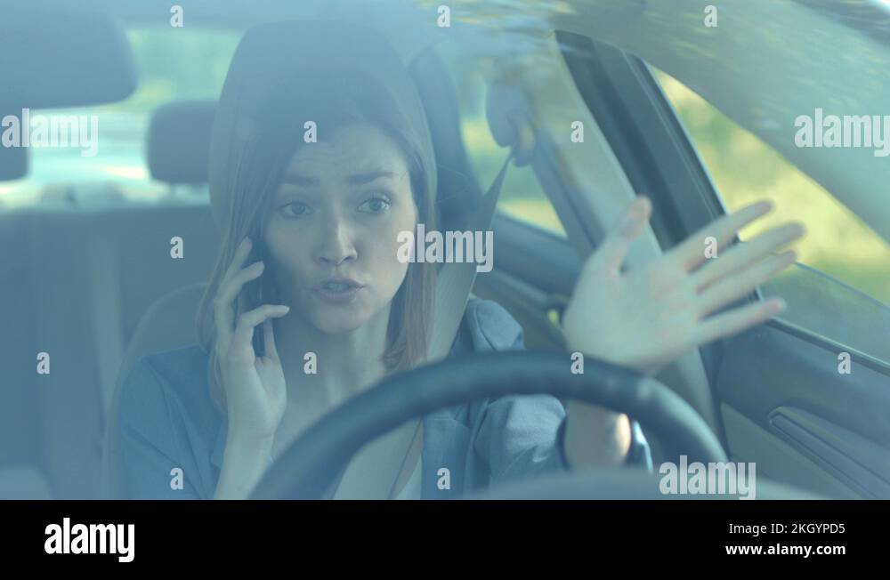 Young angry woman driver talking by phone while driving a car serious ...