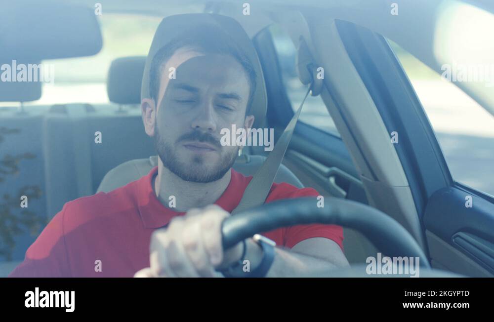 Close up young smiling man driving a car on a road trip sunset sunlight ...