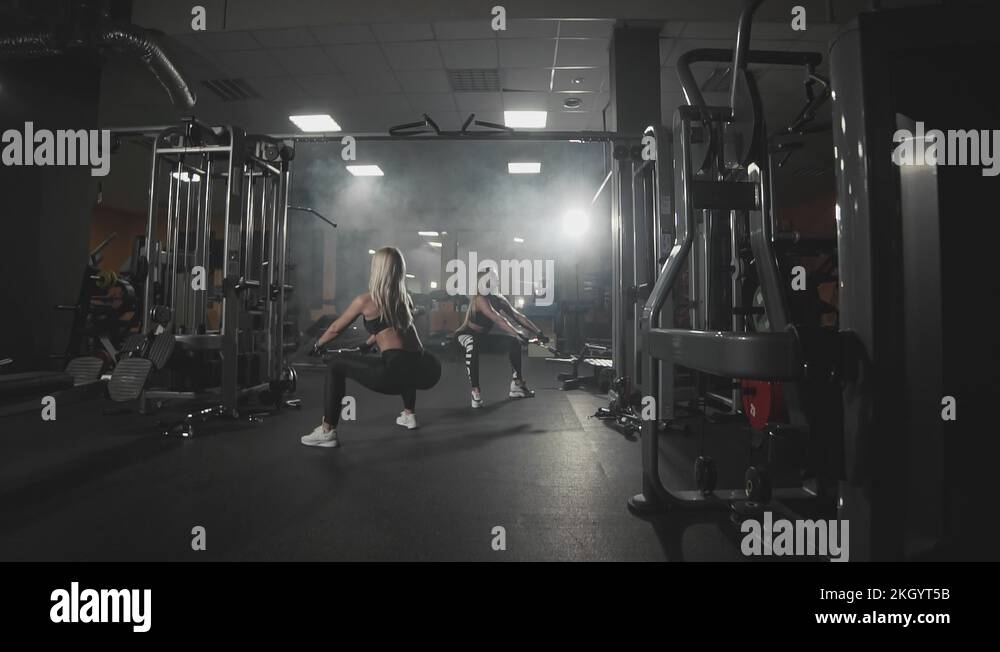 Fitness woman squat for strengthening leg. Blonde squat in simulator in ...