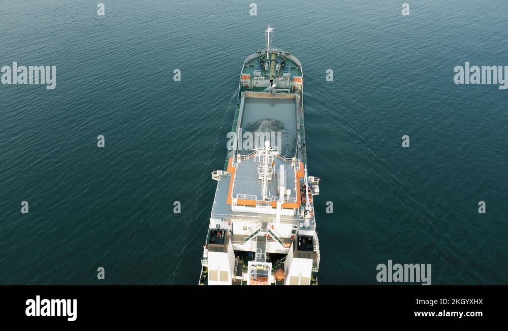 Industrial cargo freighter ship leaving port, top down aerial view ...