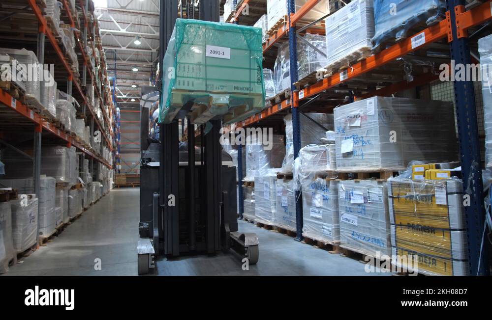 Forklift lifts a large box on the top shelf. Behind the wheel of an ...