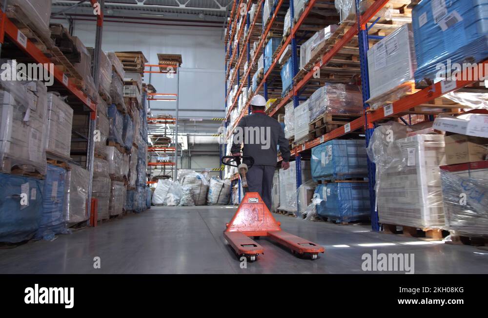 A man carries a lift for pallets in a logistic warehouse. 4K Slow Mo ...