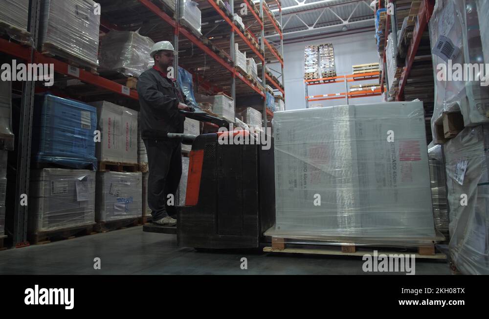 Sort goods in a logistic warehouse. The worker puts the pallets with ...