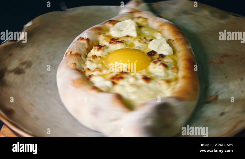 Baked open pie with yolk and cheese, spinning on a round platter ...