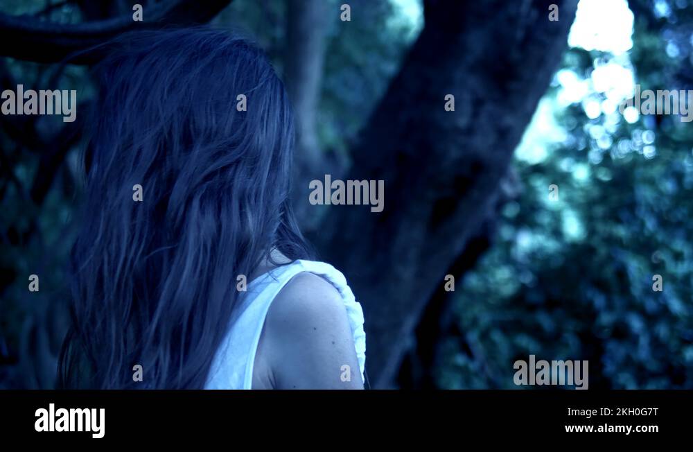 A Halloween ghost girl with long black facial hair stands in a thick ...