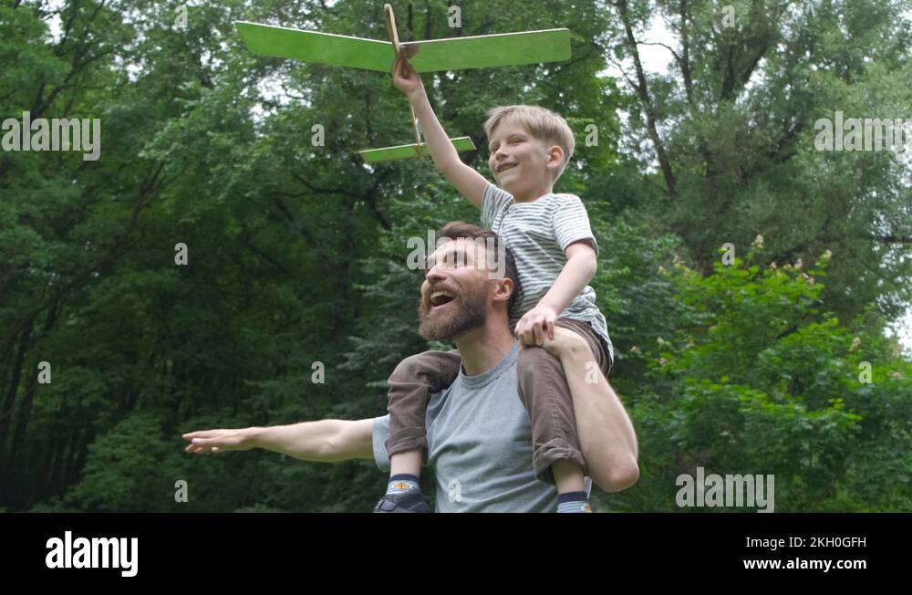 Dad and son together launch model airplane outdoors, both man and boy ...
