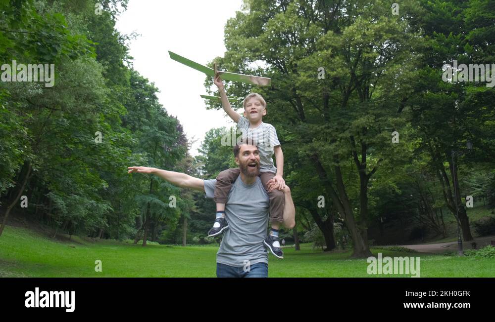 Dad and son together launch model airplane outdoors, both man and boy ...