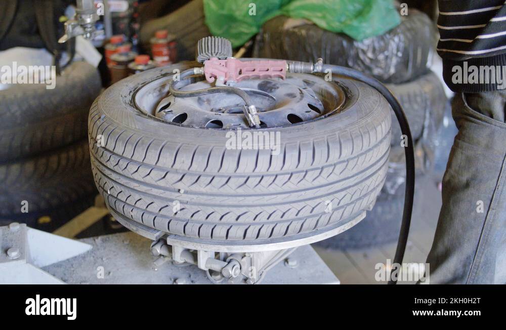 Man car technician finishes pumping tire on wheel in auto repair ...