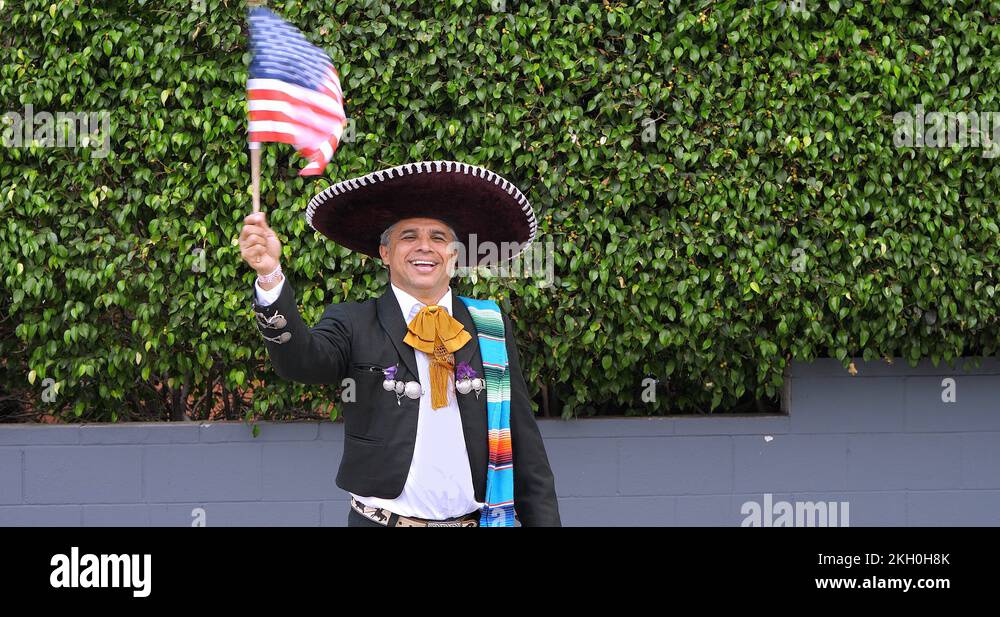 Mariachi player musician in sombrero dances and waving American flag ...