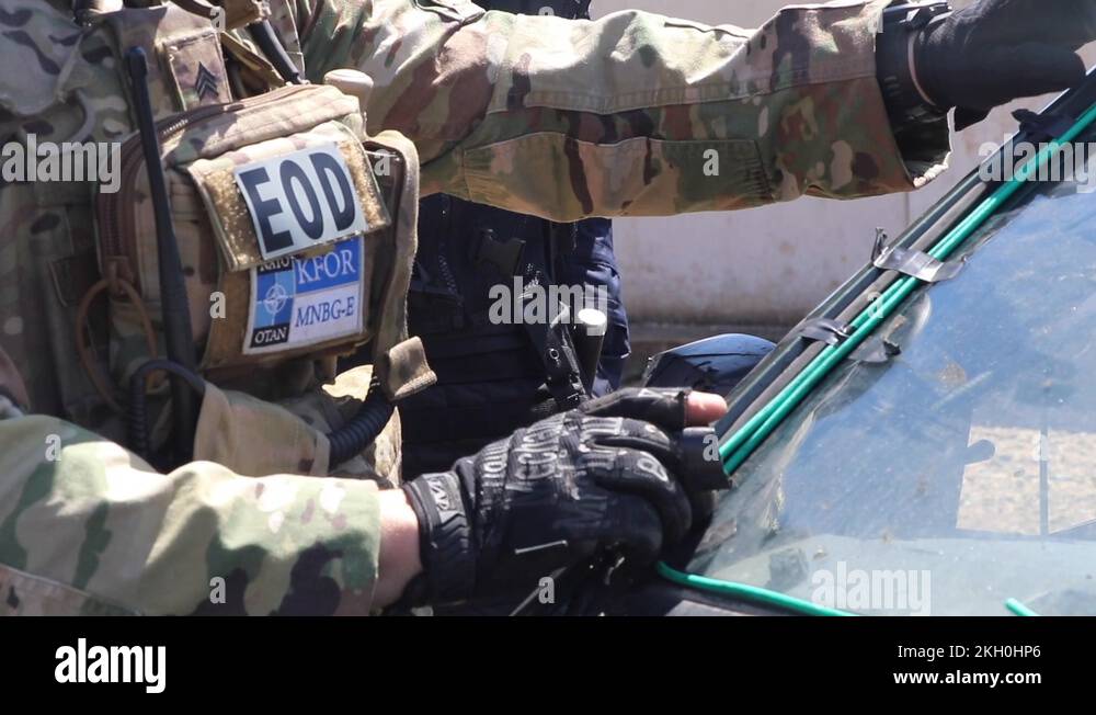 EOD soldiers securing IED wire to windscreen of vehicle with Kosovo ...