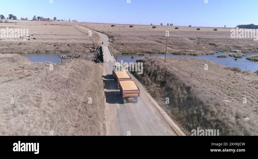 Rural African scene of tractor with trailer crossing bridge backed up ...
