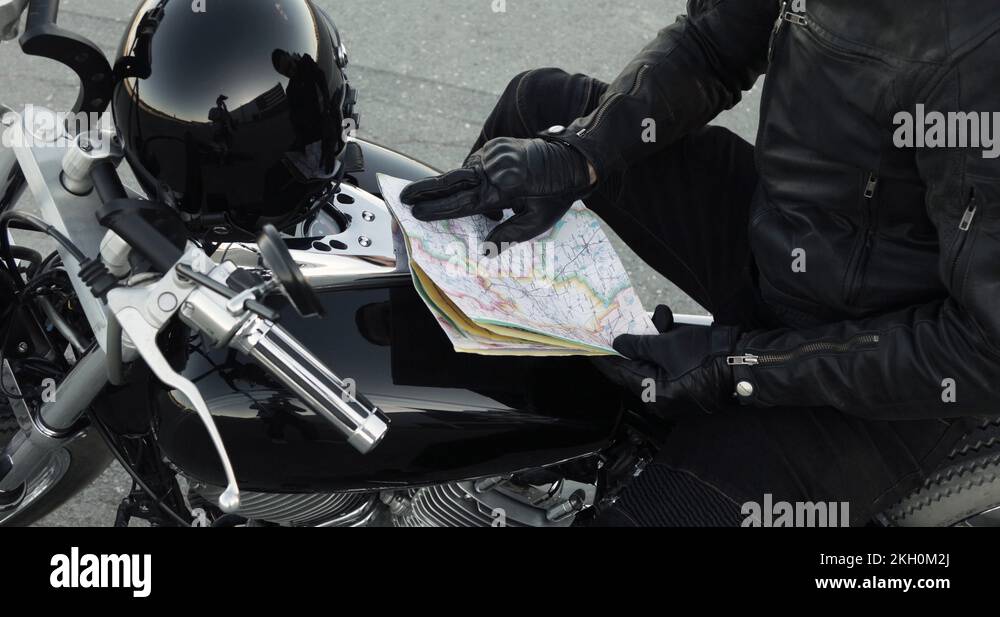 Man biker chooses the route on map sitting on his bike, hands closeup ...