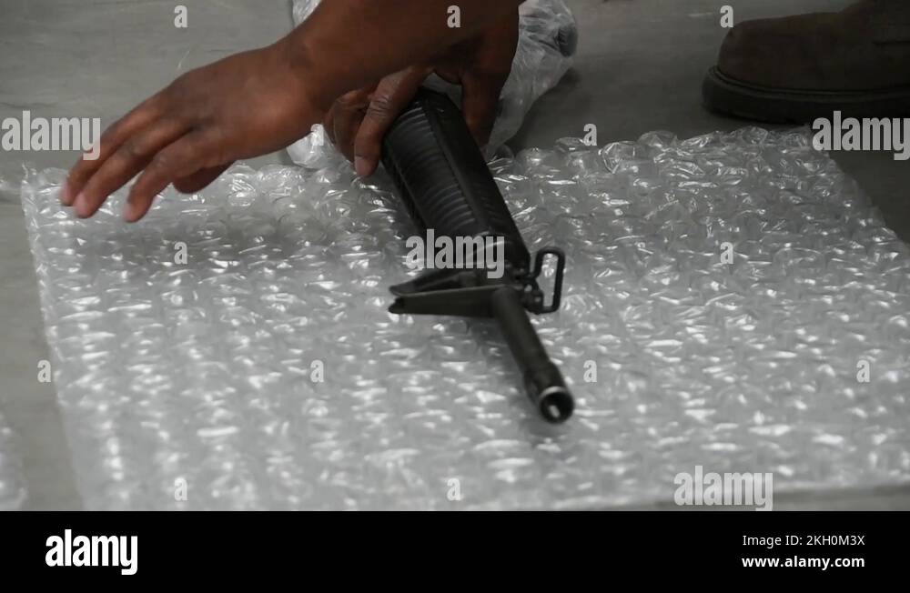 Airman wrapping and taping rifle in bubble wrap for transportation ...