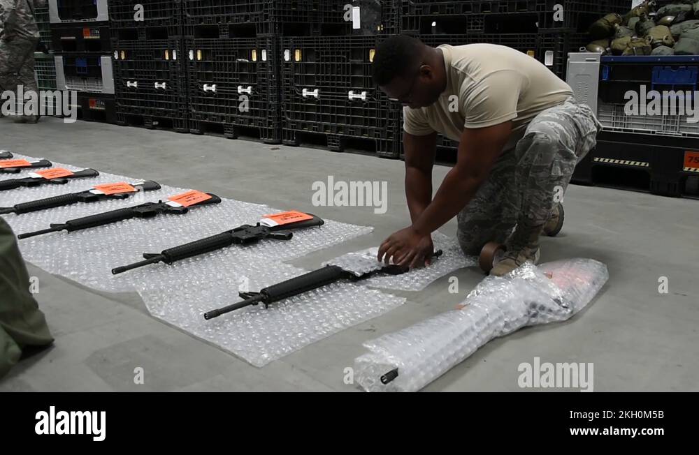 Airman packing rifle in bubble wrap inside warehouse for transportation ...