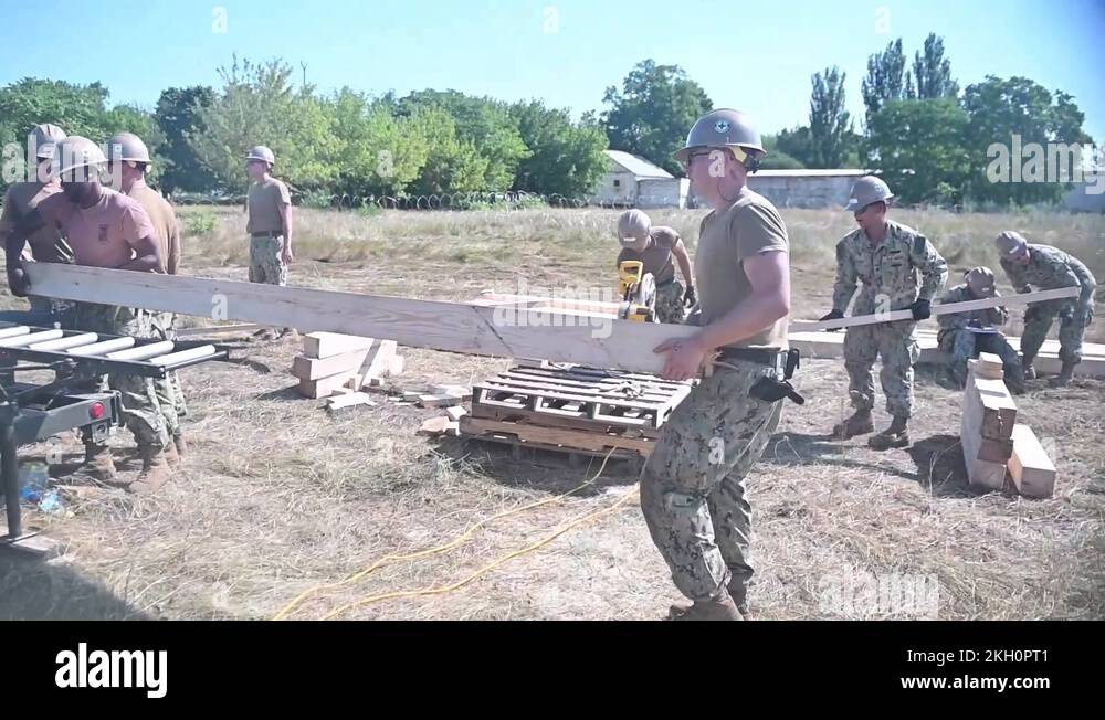 Soldiers load length of timber on rolling conveyor for cutting with ...