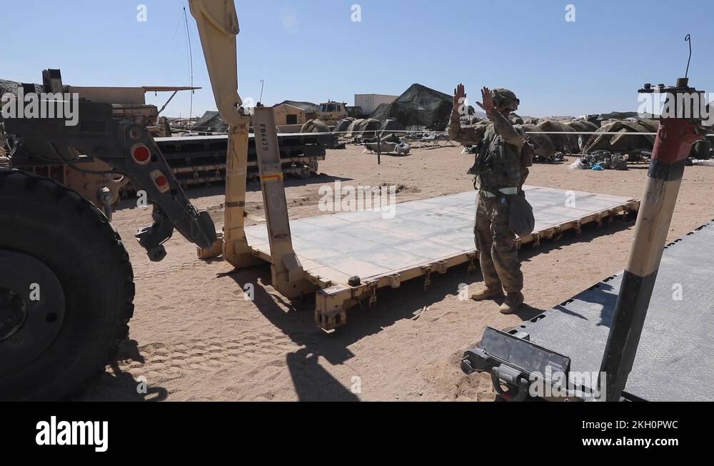 Army soldier directing truck driver offloading demountable cargo bed ...