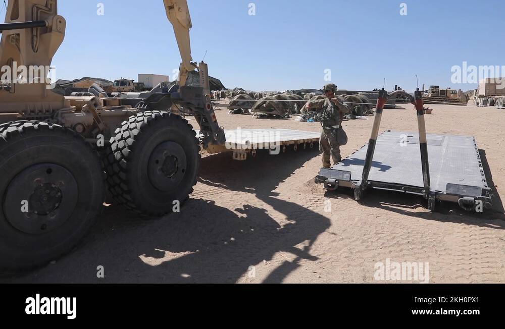 Army soldier directing truck driver offloading demountable cargo bed ...