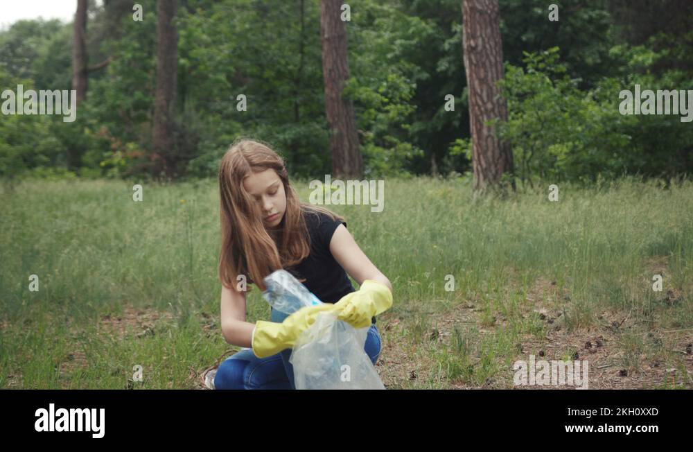 Pretty young girl collecting rubbish from the ground in a city park ...