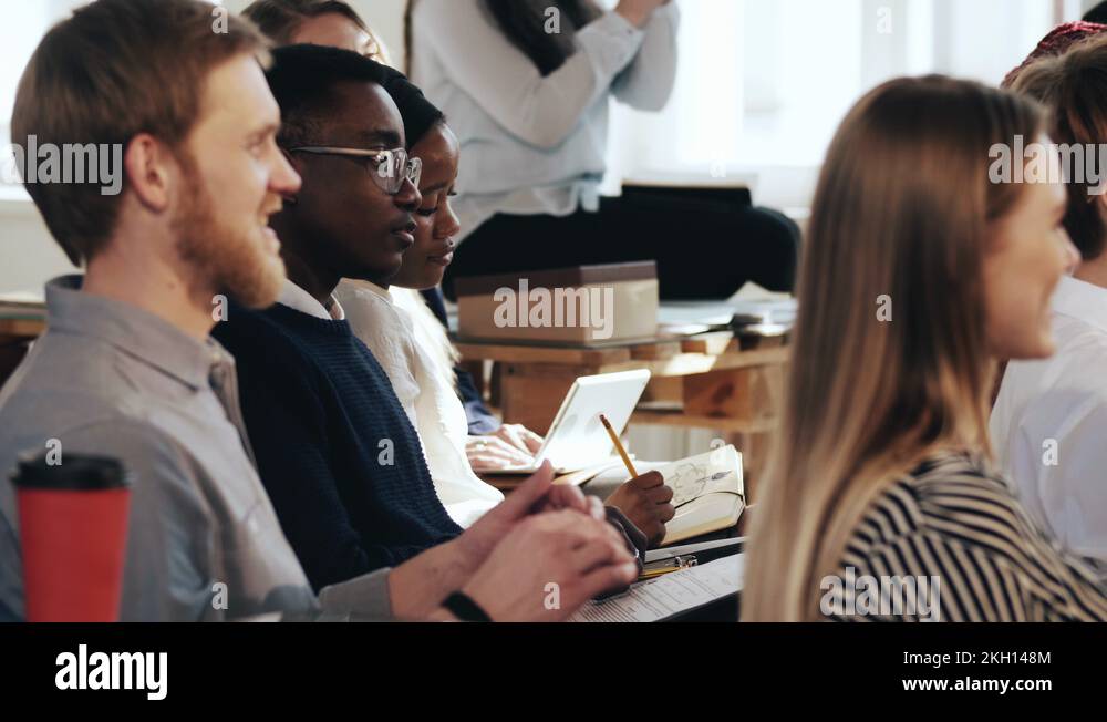 Side view close-up happy smiling young multiethnic audience clapping to ...