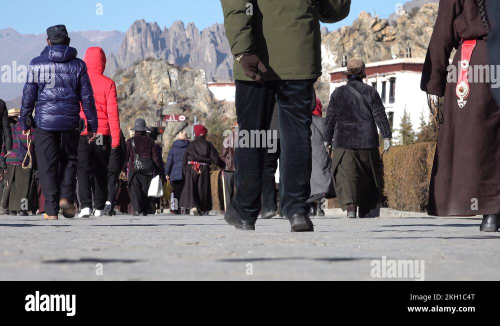Low angle of Tibetan pilgrims walking around Potala palace in Lhasa ...