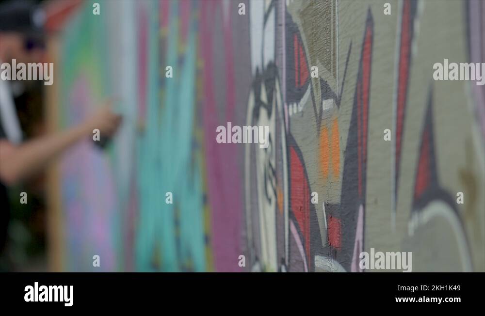 Graffiti artist spray painting wall tagging name in street art style ...