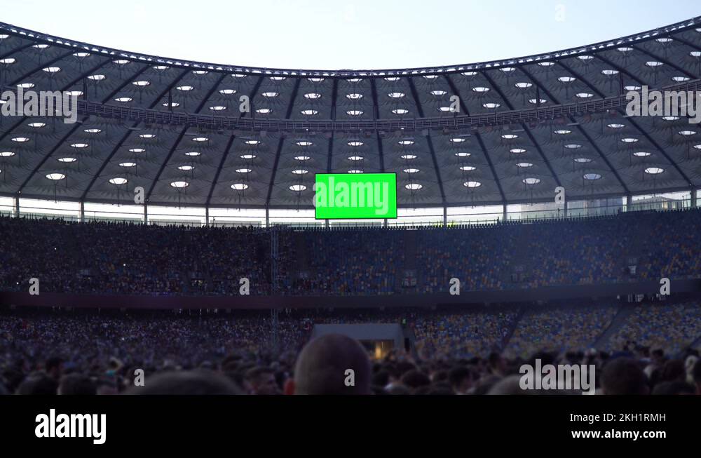 Crowd of people stand in an open stadium with Big TV Green Screen Stock ...
