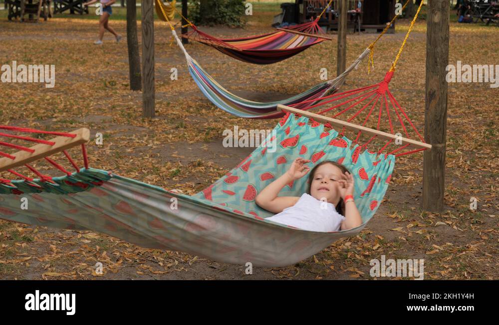 Little child girl has fun rest lying swaying in hammock in a park Stock ...
