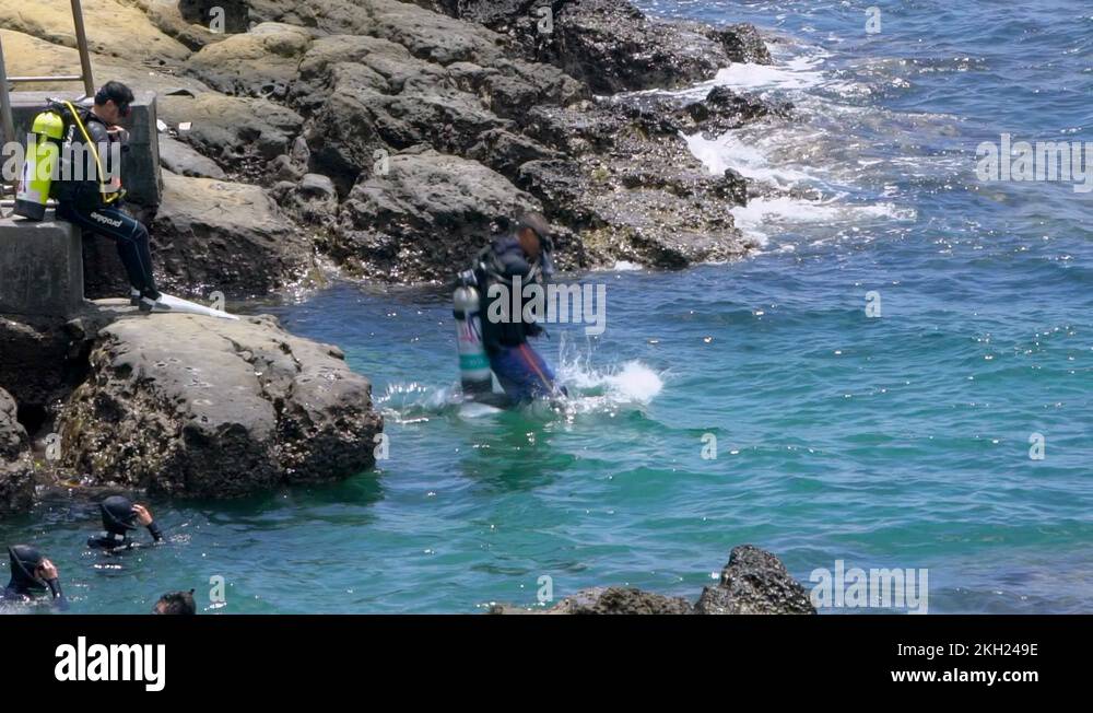Slow Motion of scuba diver jumping in the water from rock of tropical ...
