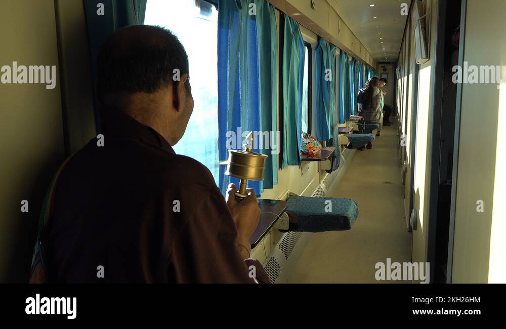 Tibetan pilgrim spins hand prayer wheel inside carriage of Qinghai ...
