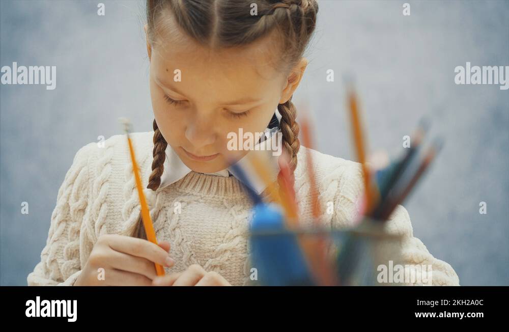 Nice girl with plaits holding yellow pencil and deciding what to draw ...