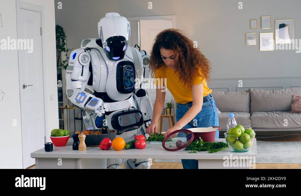 Young woman and a cyborg cook dinner together. Robot, cyborg and human ...