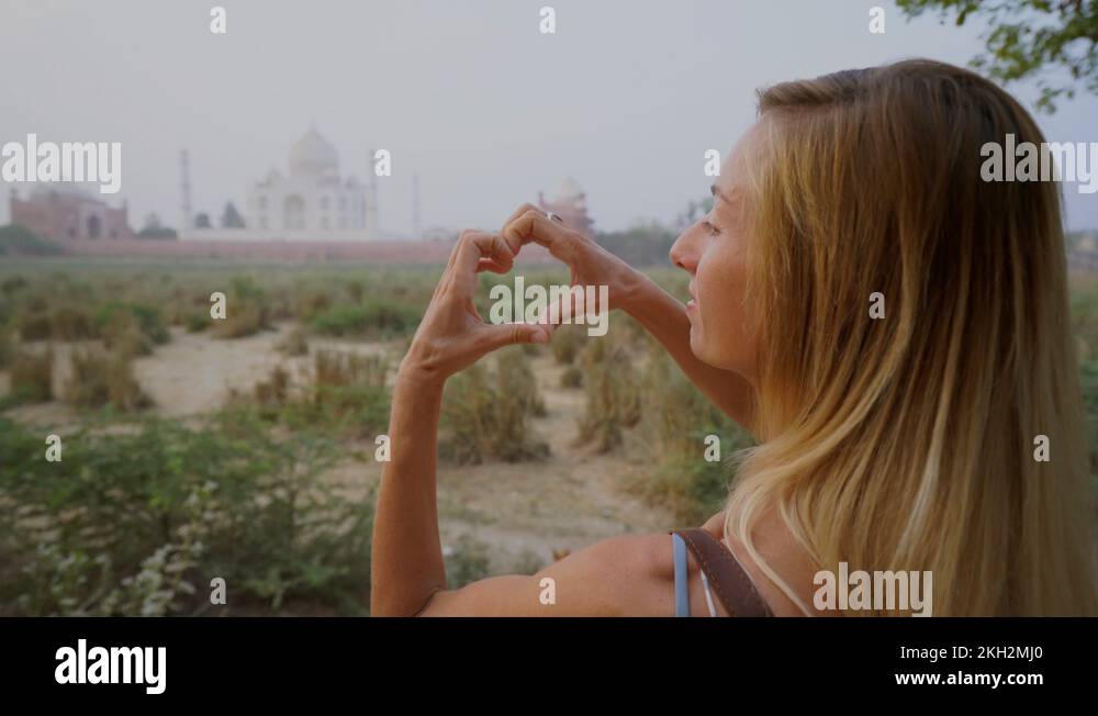 Young woman loving the famous Taj Mahal at sunset making heart shape ...