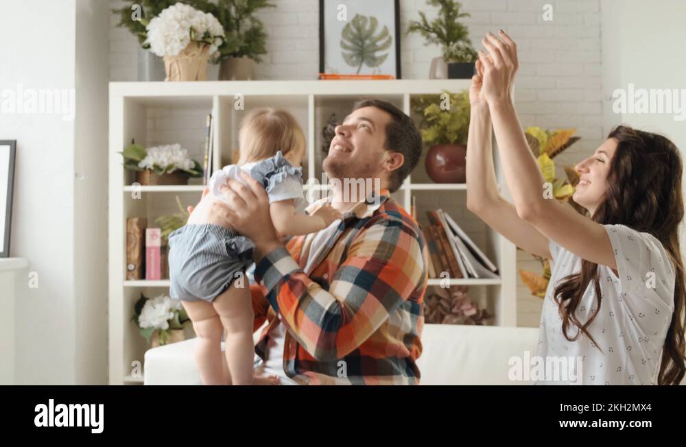 Young happy father throws up his baby daughter playing with her ...
