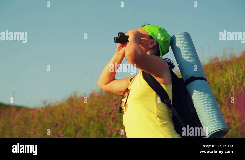 Woman hiker on a hill with a backpack behind her, looking through ...