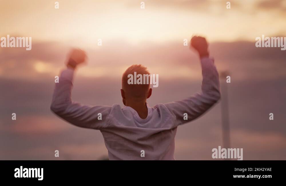 Winner man making win gesture raising hand yellow scarlet sunset sky ...