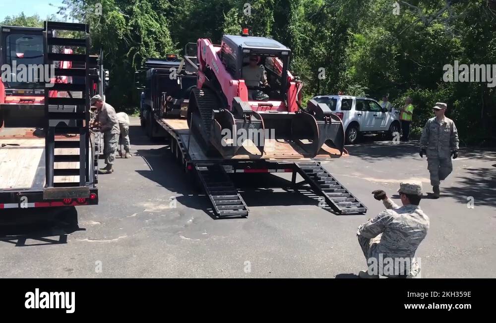 National Guard soldier directing Bobcat driving off trailer for tornado ...
