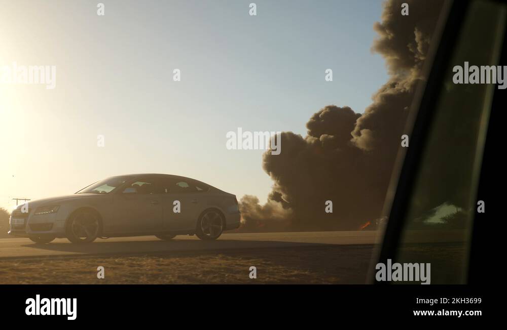Side view tracking car ride on freeway past truck on fire. Cloud of ...