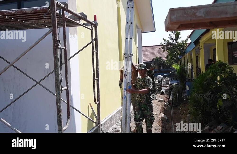 Soldiers moving step ladder at school construction site in Indonesia ...
