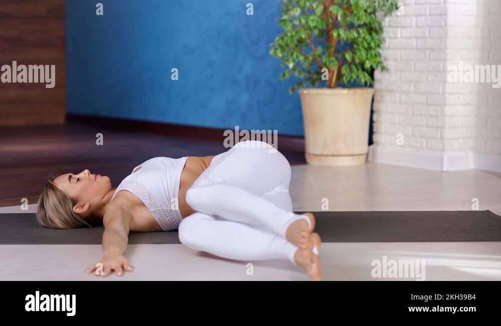 Yogi young woman relaxing practicing yoga lifting leg from one side to ...