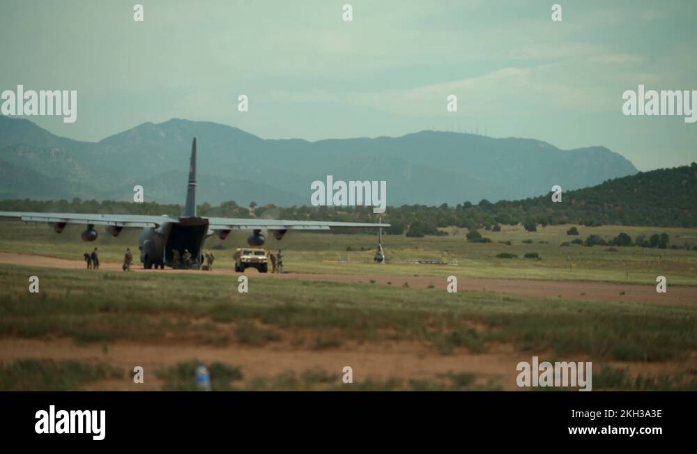 Military jeep and soldiers at rear door of C-130 Hercules in desert ...