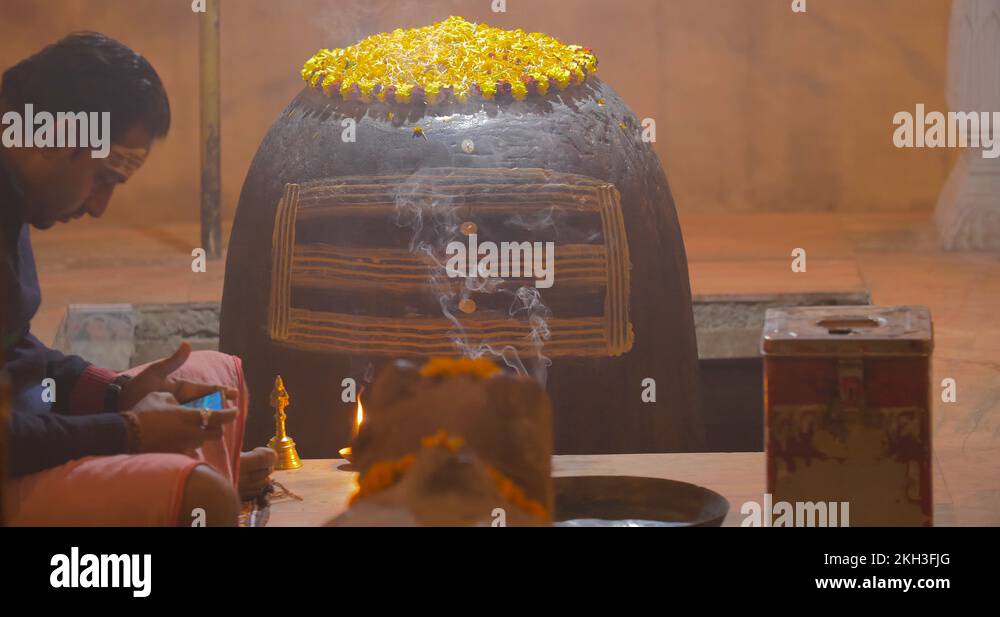 Priest watching phone inside Hindu temple in Varanasi during prayer ...