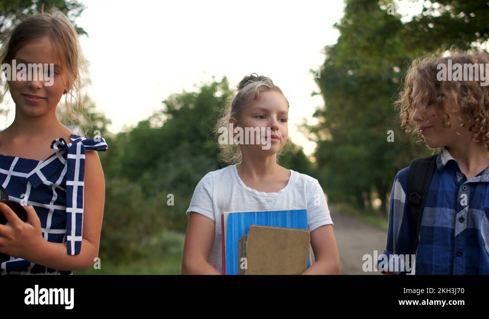 Happy children come back from school and laugh cheerfully. Carry books ...