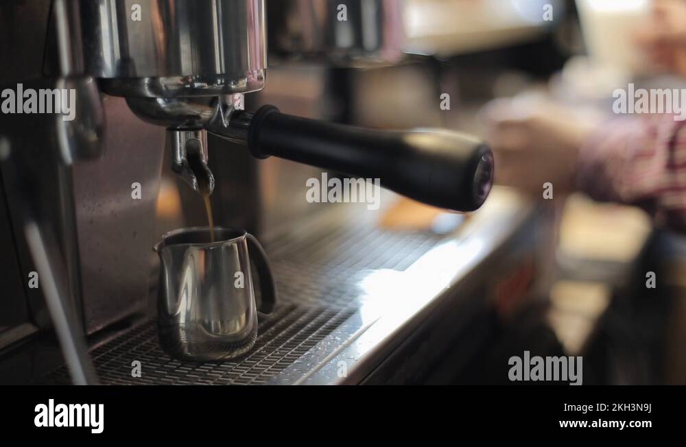 Espresso coffee machine finishes pouring espresso into a steel pitcher ...