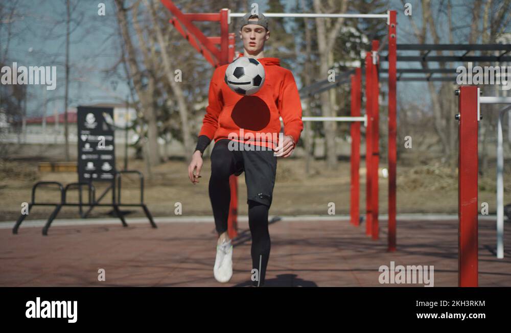 A young guy throws a soccer ball his feet. Street football. Slow motion ...