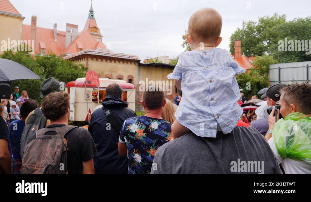 Parent father stay in crowd people holds a child sitting on shoulders ...