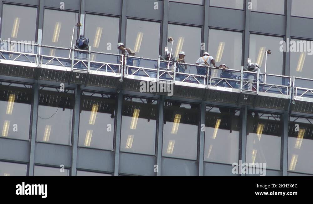 Construction Workers Making Skyscraper Repairs To Glass Windows Using A ...