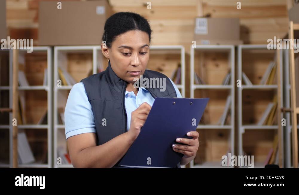 Attentive Black Female Post Office Employee Filling out Checklist Stock ...