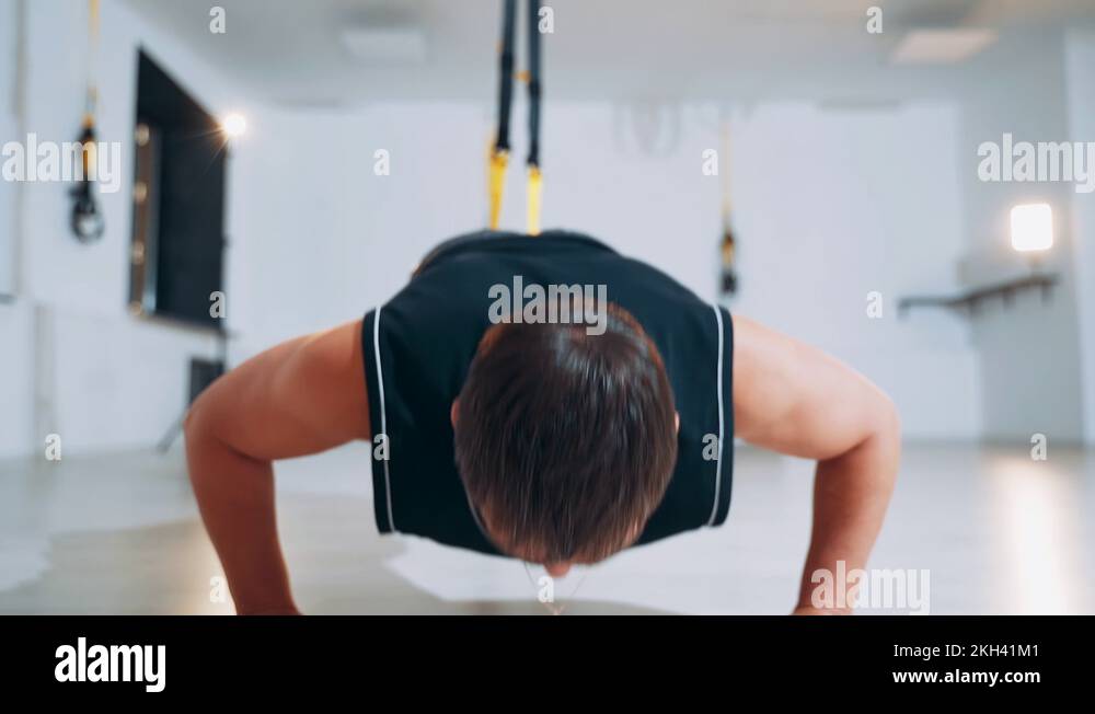 Using TRX bands, doing push-ups and torso rotations with legs suspended ...
