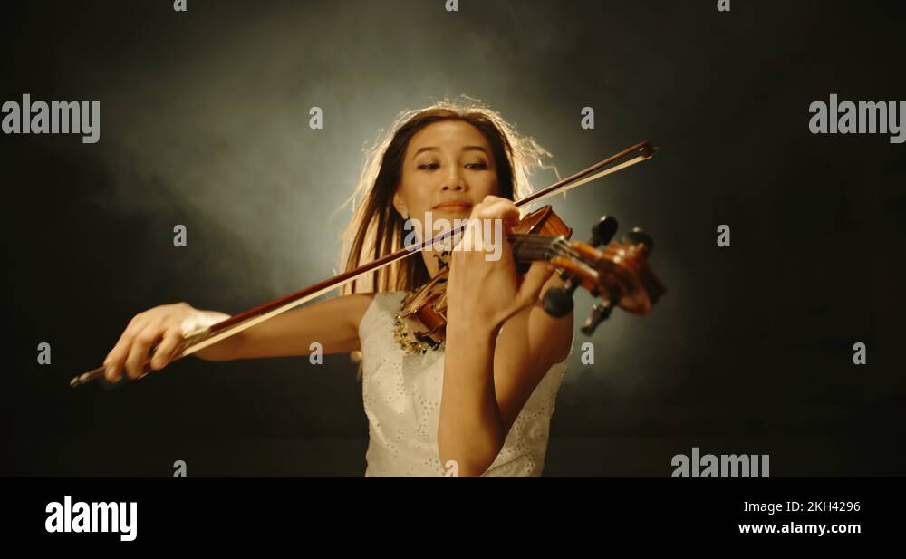 Female violin player performing sheet music on stage. Experienced asian ...