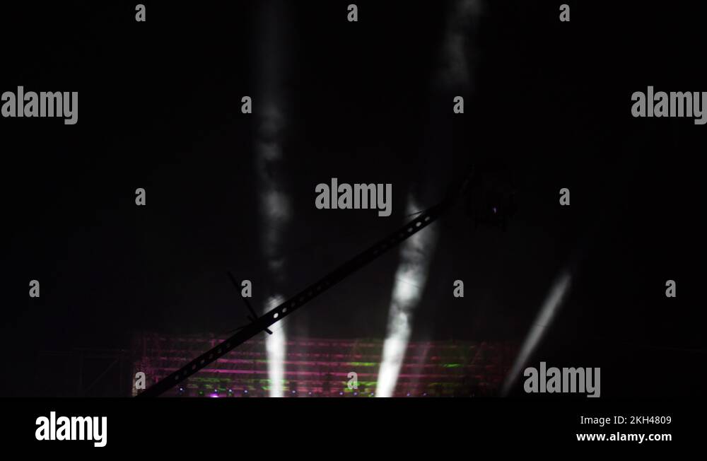 Flashing light beams from stage lights and a camera crane silhouette ...